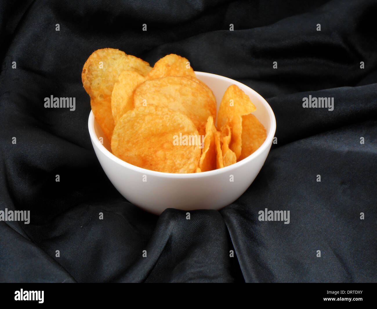 Chips in a plate on black material background Stock Photo - Alamy