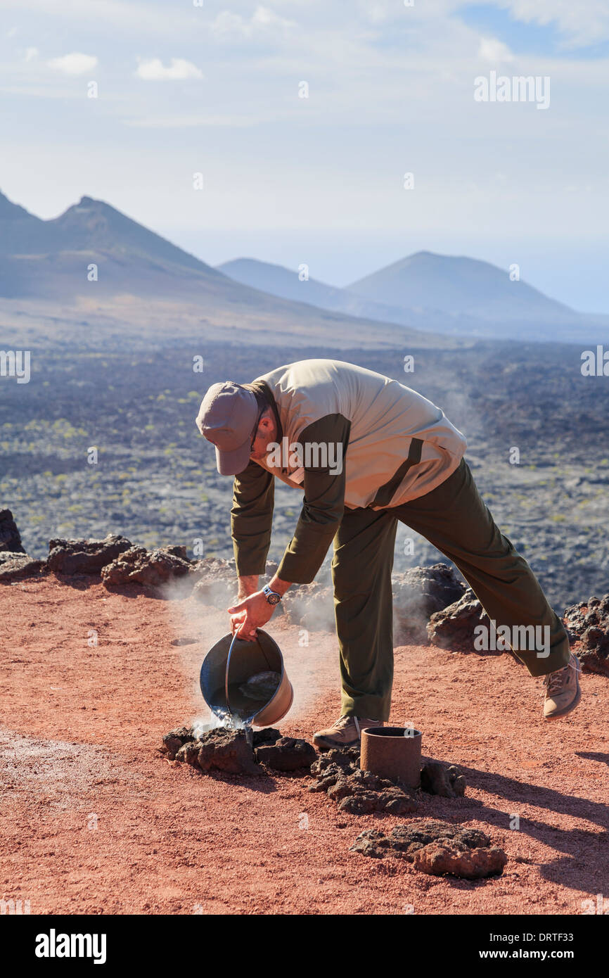 Employee man pouring water into a vent to create a steam geyser on ...