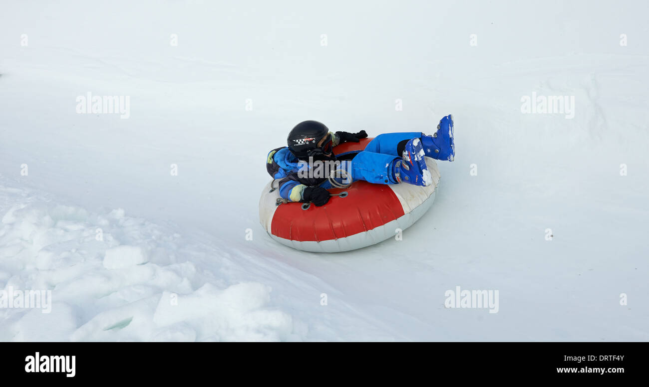 Young boy enjoys a snow tube ride Stock Photo - Alamy