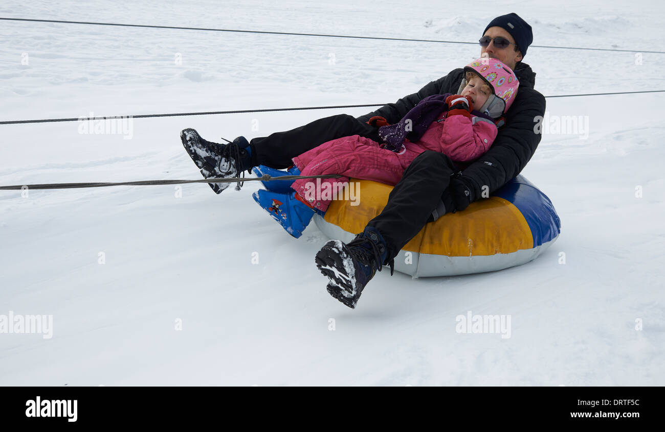 Father and daughter having fun in snow inner tube - snowtubing Stock ...