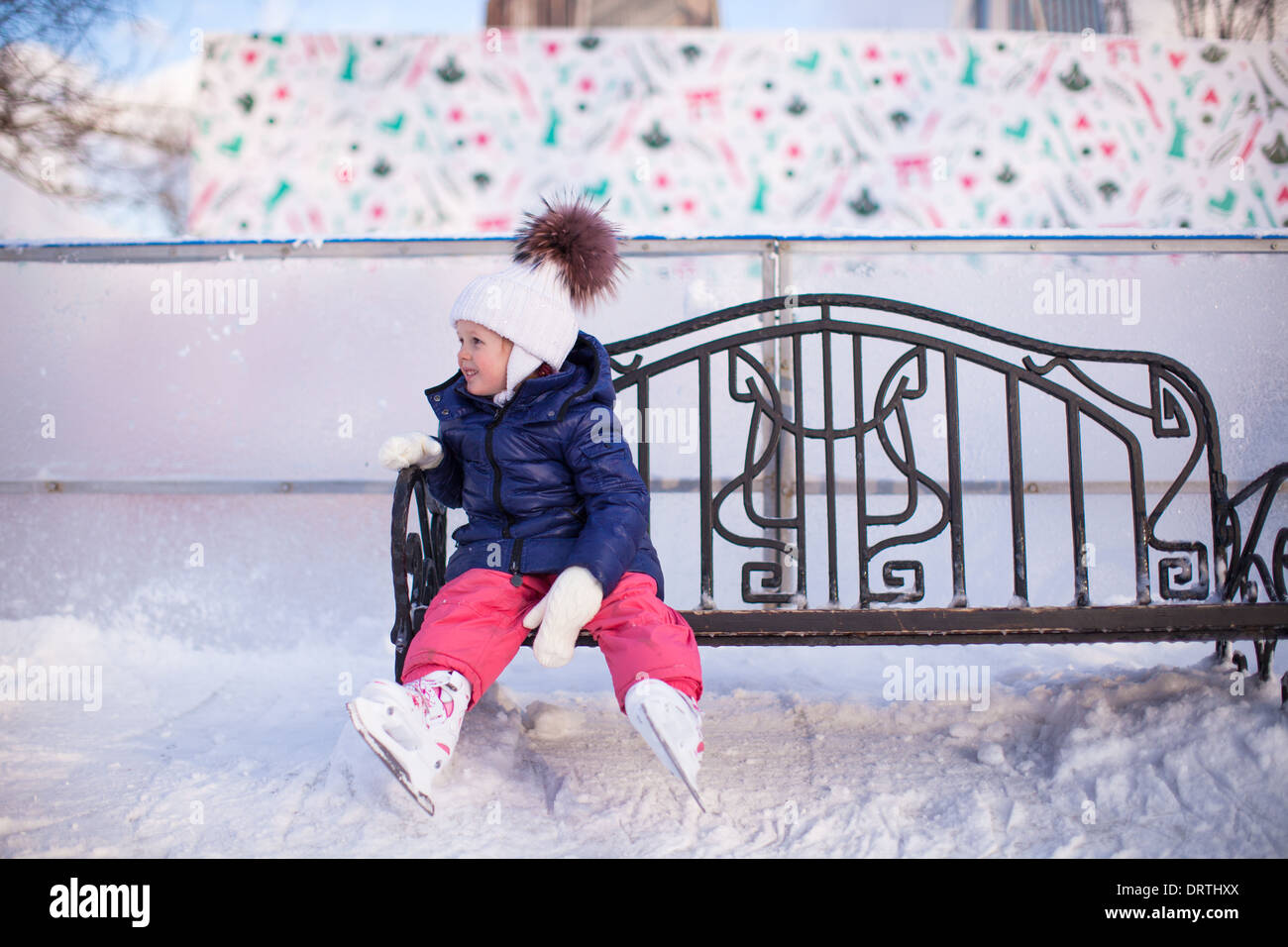 Little girl sitting on a bench in the skating rink Stock Photo - Alamy