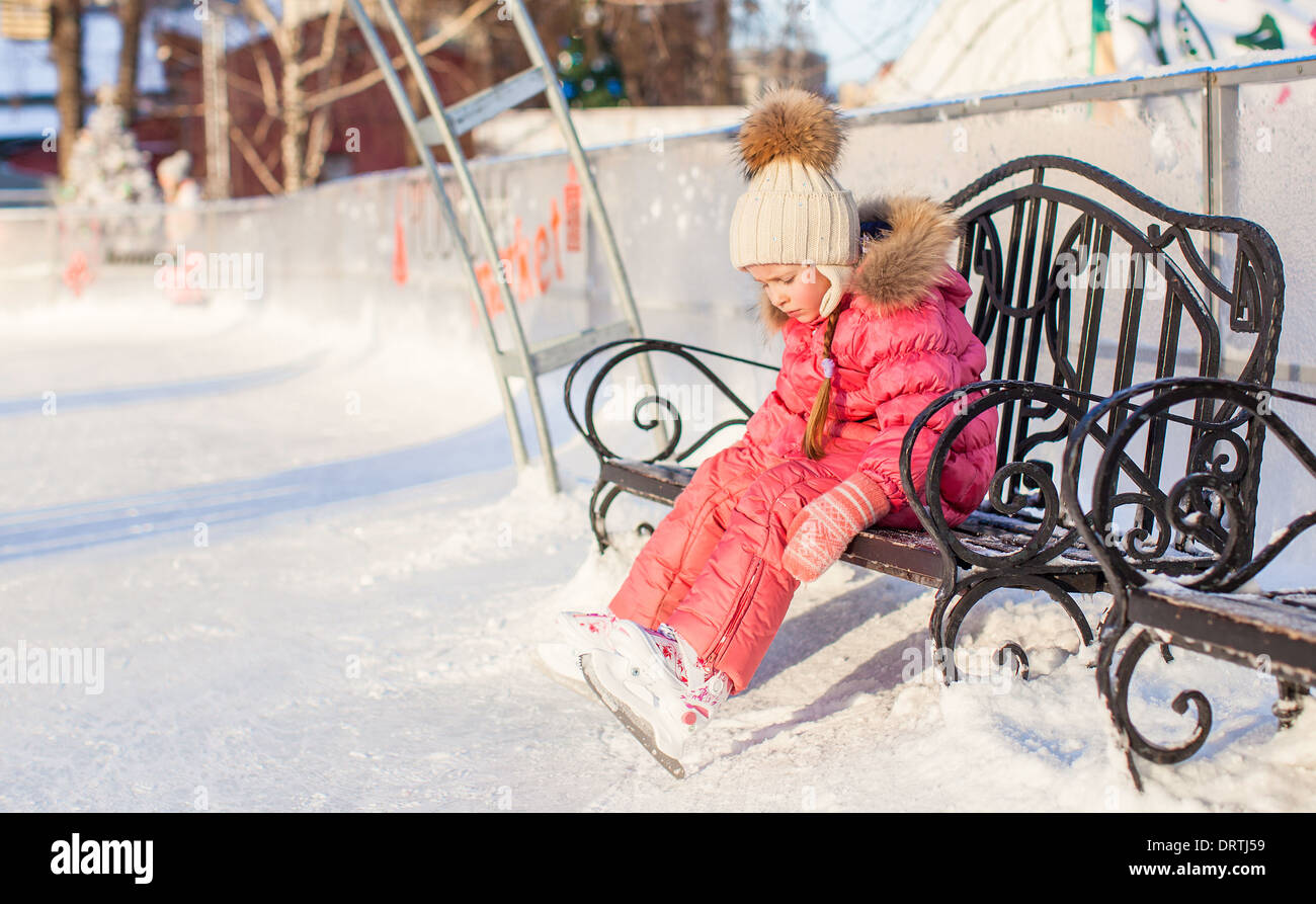 Little sad girl sitting on a bench in the skating rink Stock Photo - Alamy