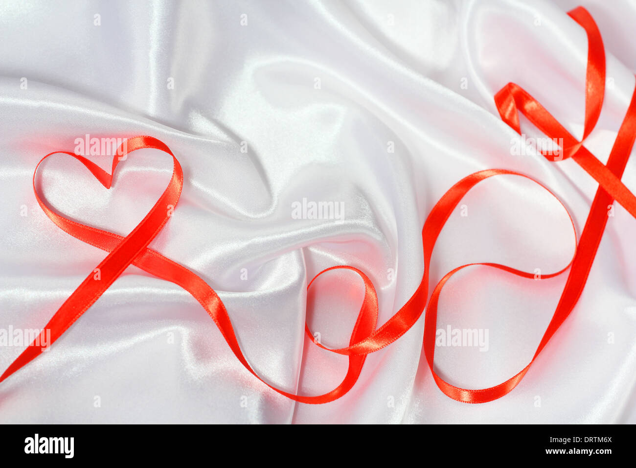 Red satin glossy ribbon heart over white silk background Stock Photo ...