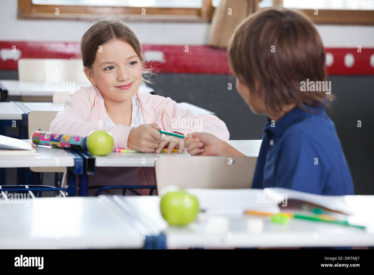 Little Girl Giving Pencil To Boy In Classroom Stock Photo - Alamy