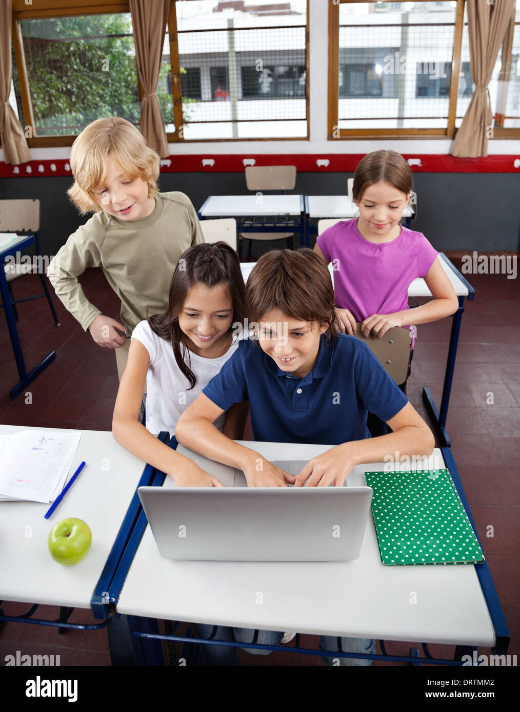 Schoolchildren Using Laptop At Desk In Classroom Stock Photo - Alamy