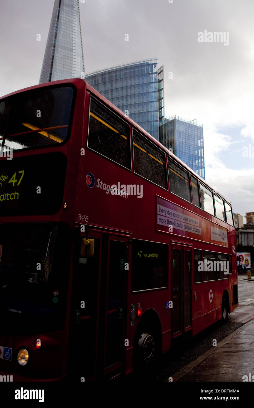 Red bus driving by London Bridge, the Shard in the background Stock ...