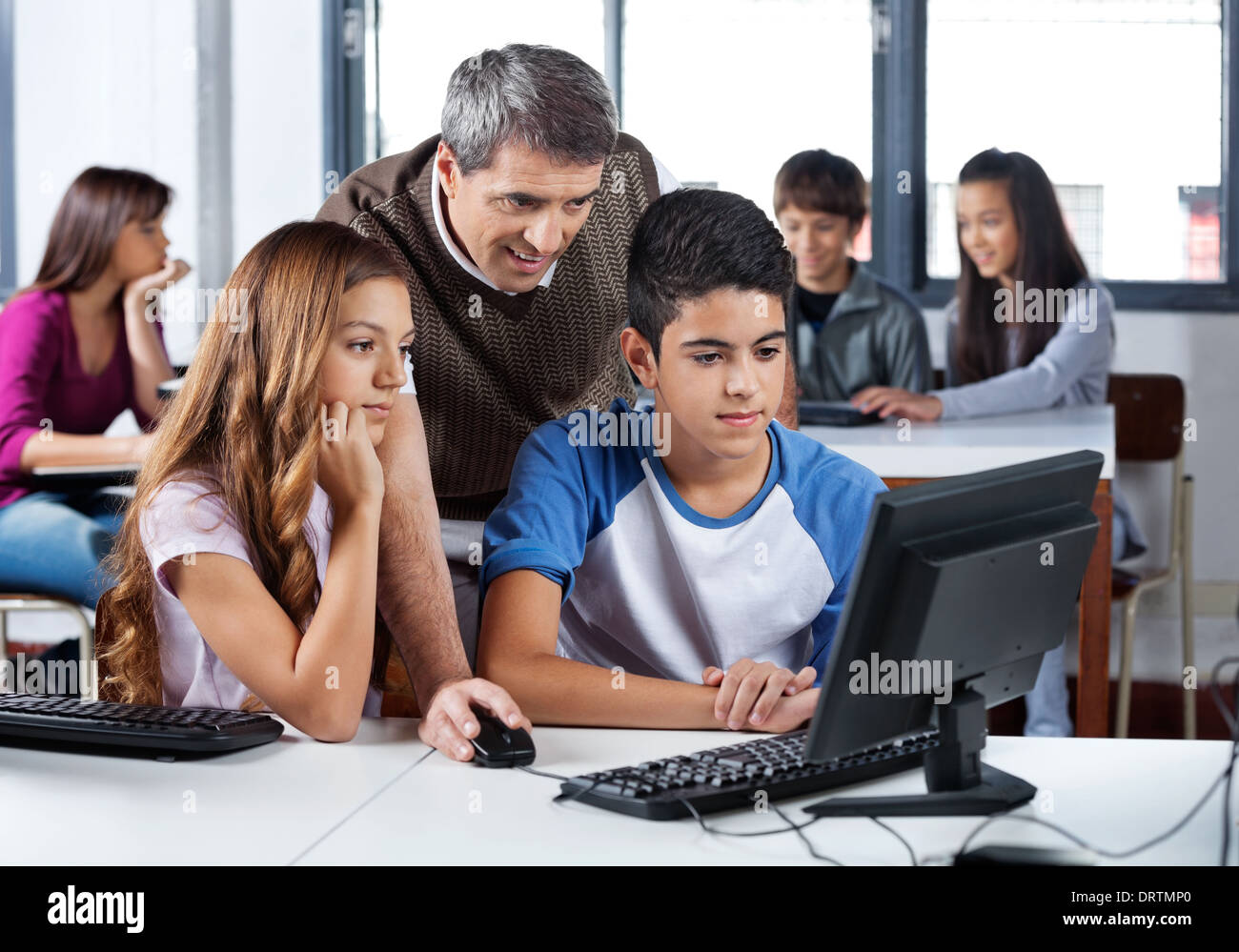 Male Teacher Assisting Students In Computer Class Stock Photo - Alamy