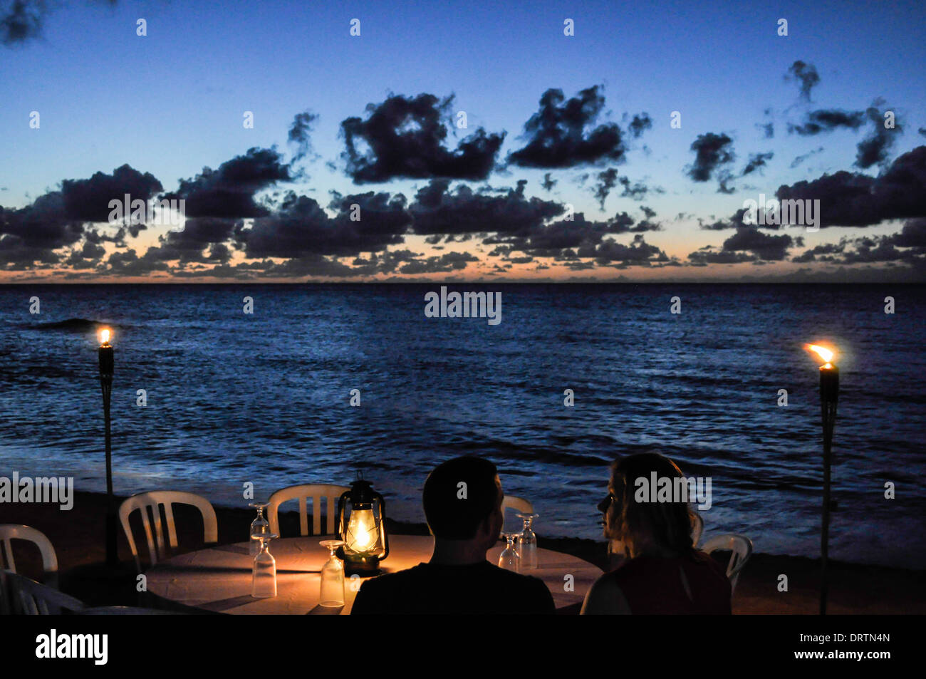 A couple at a beach overlooking the Caribbean, getting ready for dinner ...