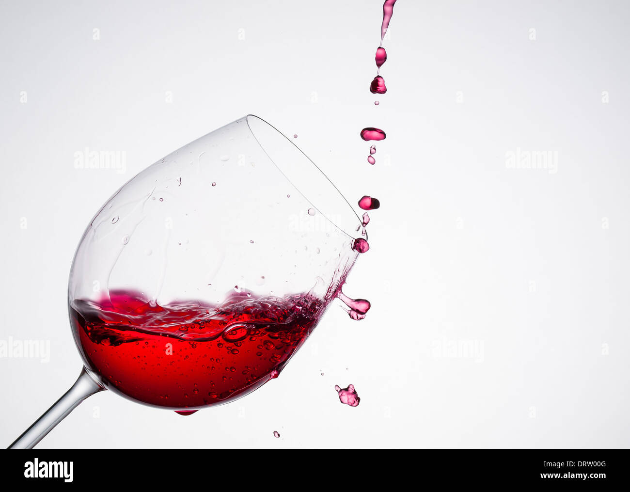 Wine pouring into a glass in diagonal composition and white background ...