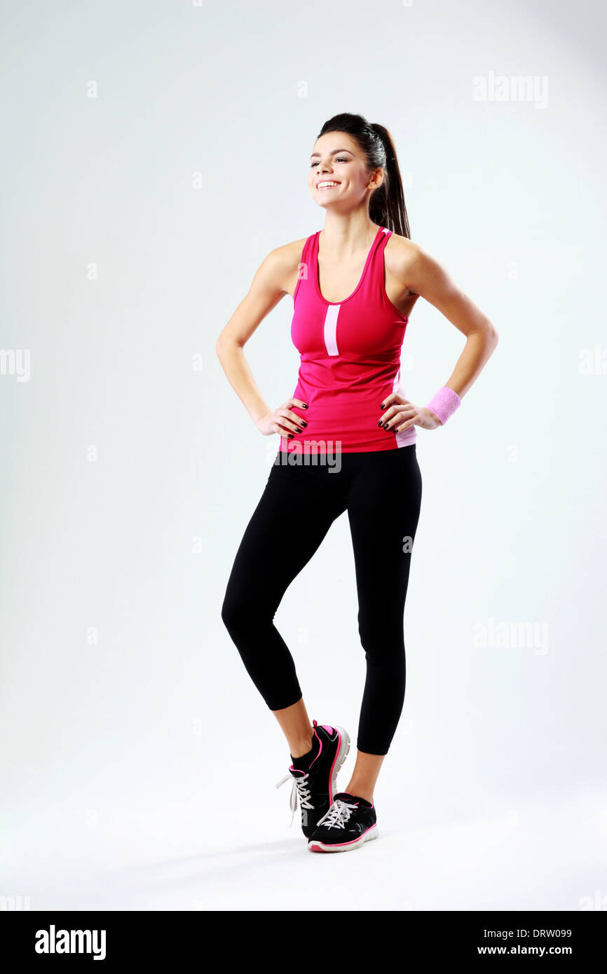 Full-length portrait of a young smiling sport woman on gray background ...