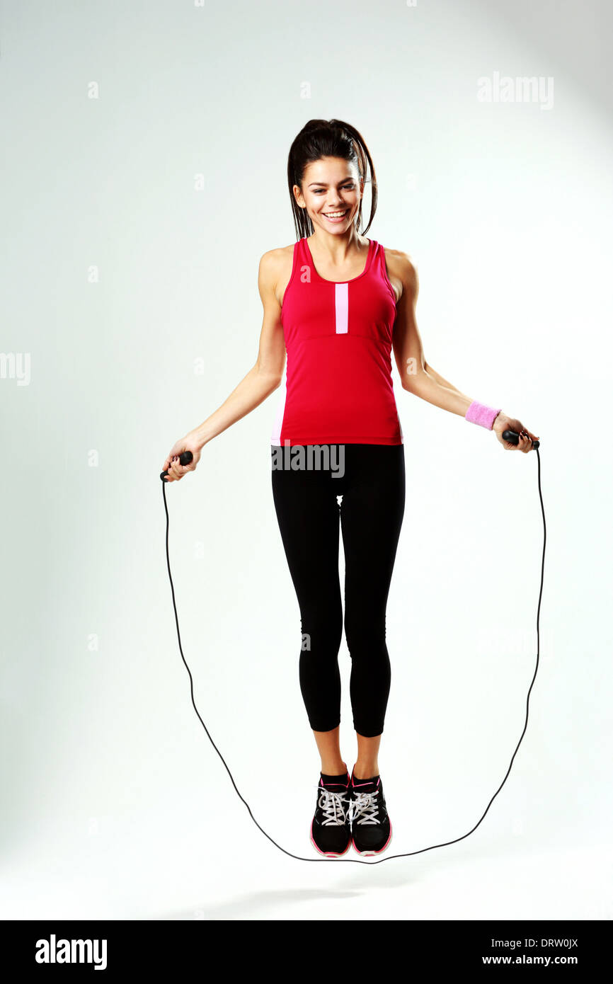 Young smiling woman jumping rope on a gray background Stock Photo - Alamy