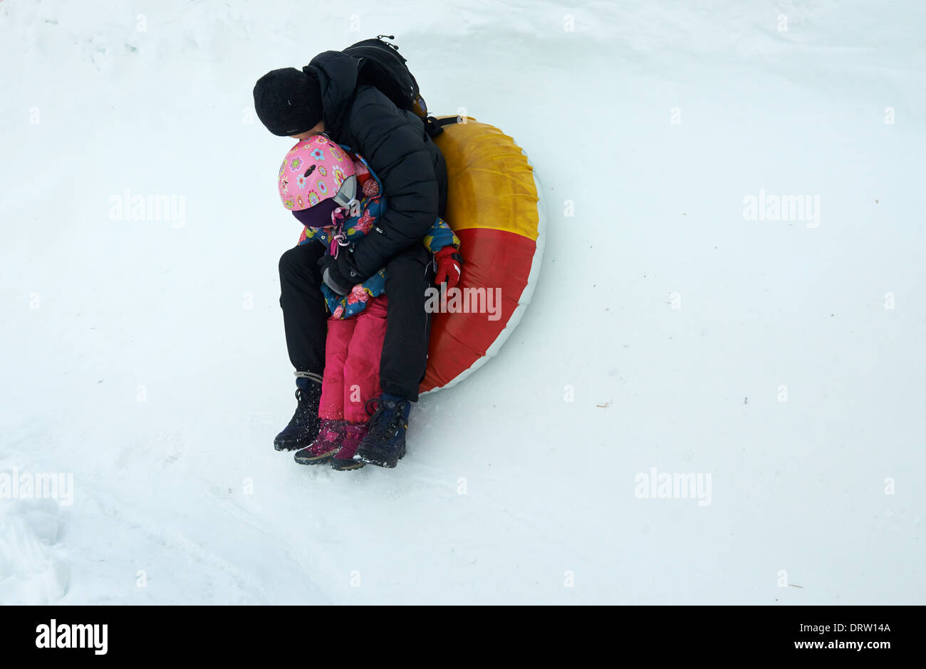 Father and daughter having fun in snow inner tube - snowtubing Stock ...