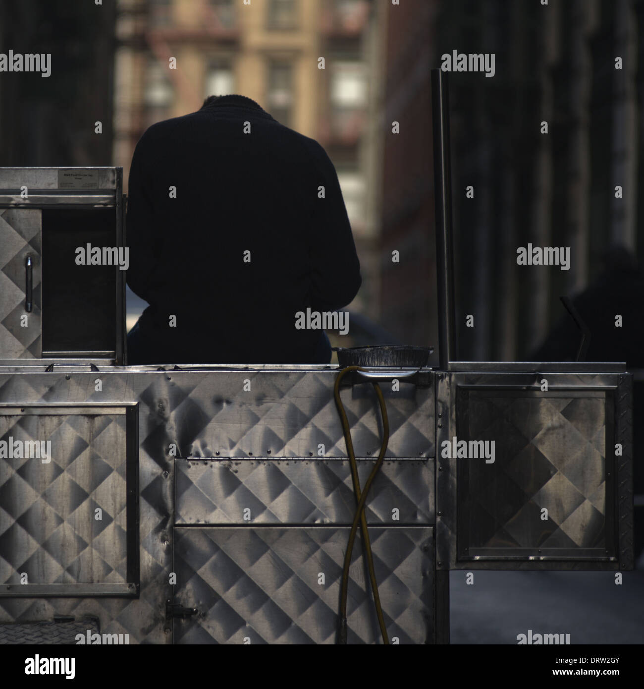 Man sitting on steel box nodding forward Stock Photo - Alamy