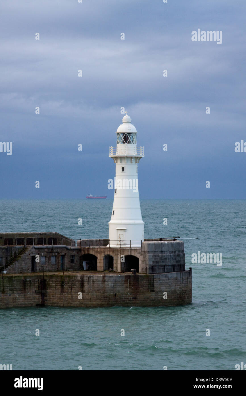 Entrance to Dover harbour showing lighthouse and large ship on horizon ...