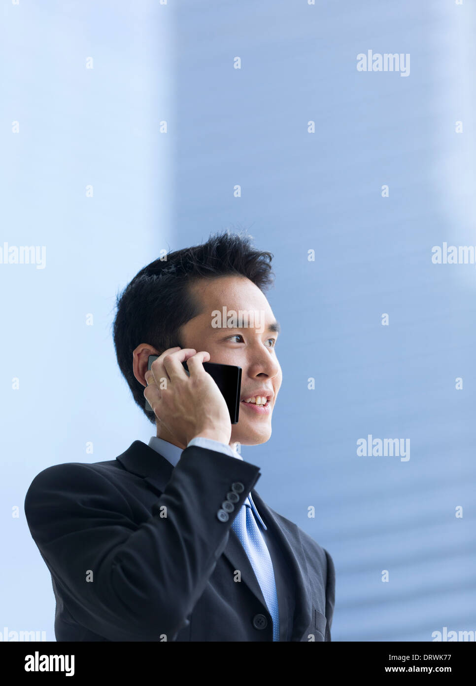Chinese business Man using his cell phone outdoors in modern Asian city ...