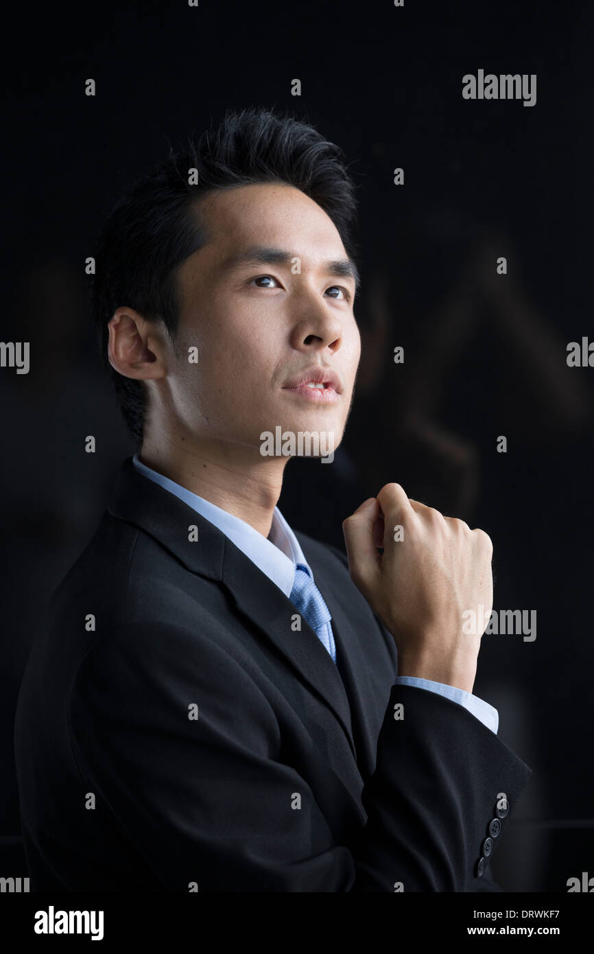 Chinese Business man leaning on a black wall. Handsome young Chinese ...