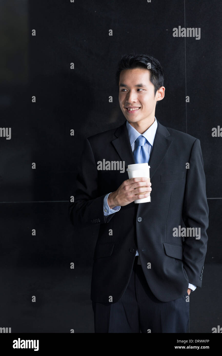 Chinese Business man leaning on a black wall. Handsome young Chinese ...