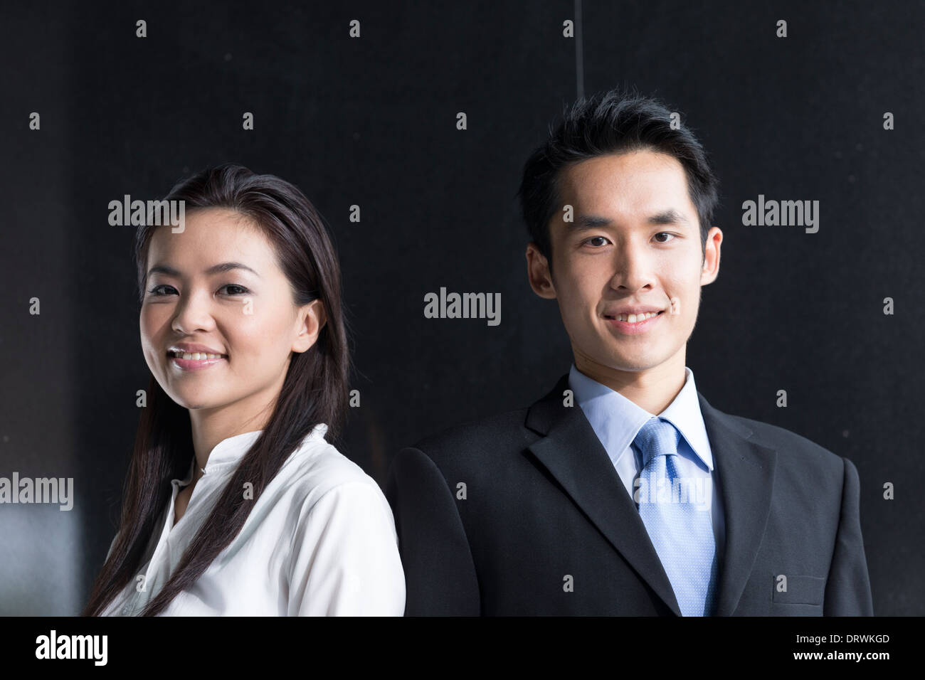 Portrait of two serious Chinese business people standing in front of a ...