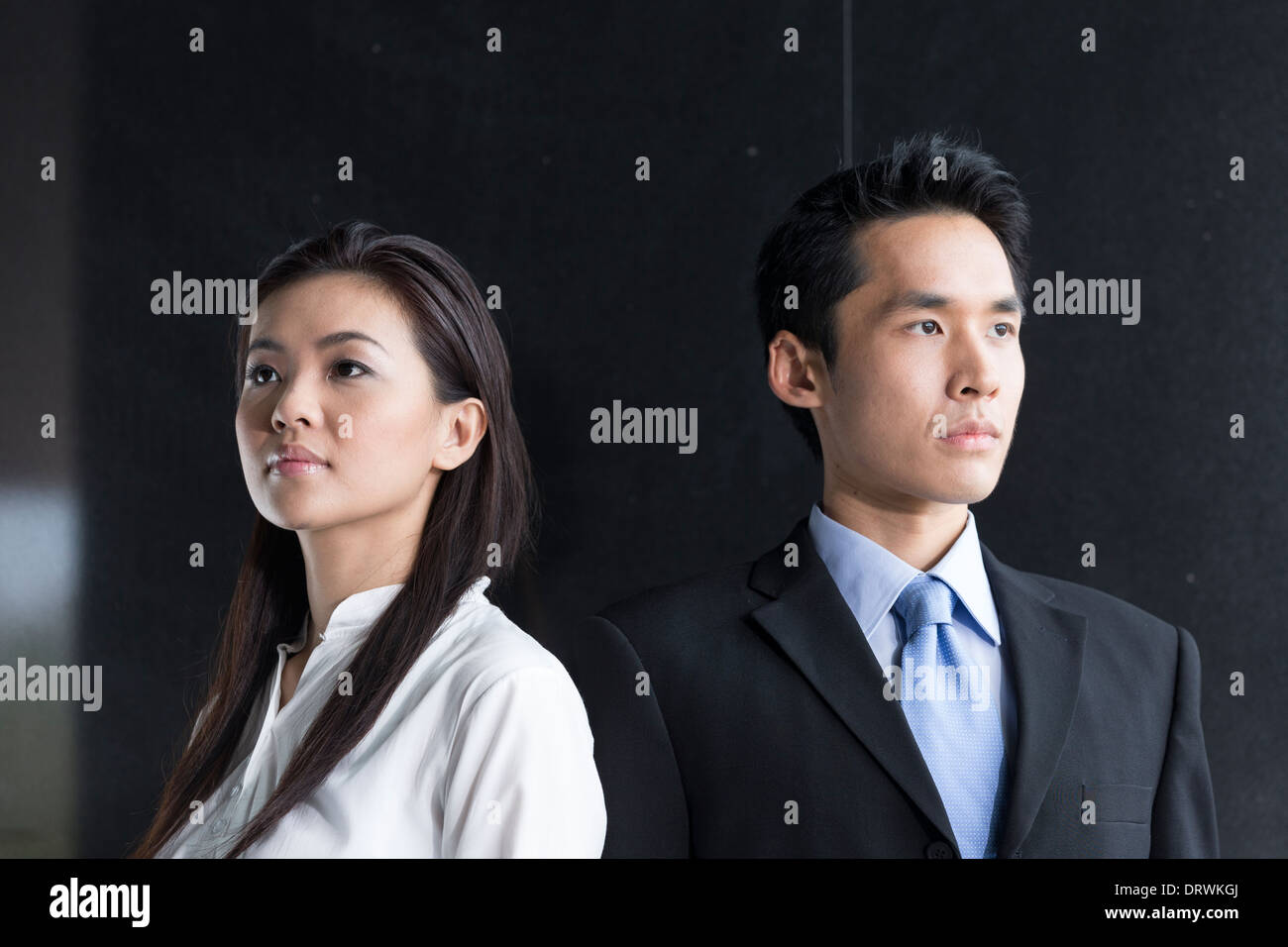 Portrait of two serious Chinese business people standing in front of a ...