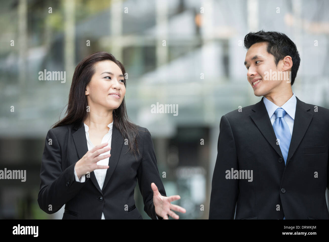 Happy Chinese Business colleagues walking outside office & talking to ...