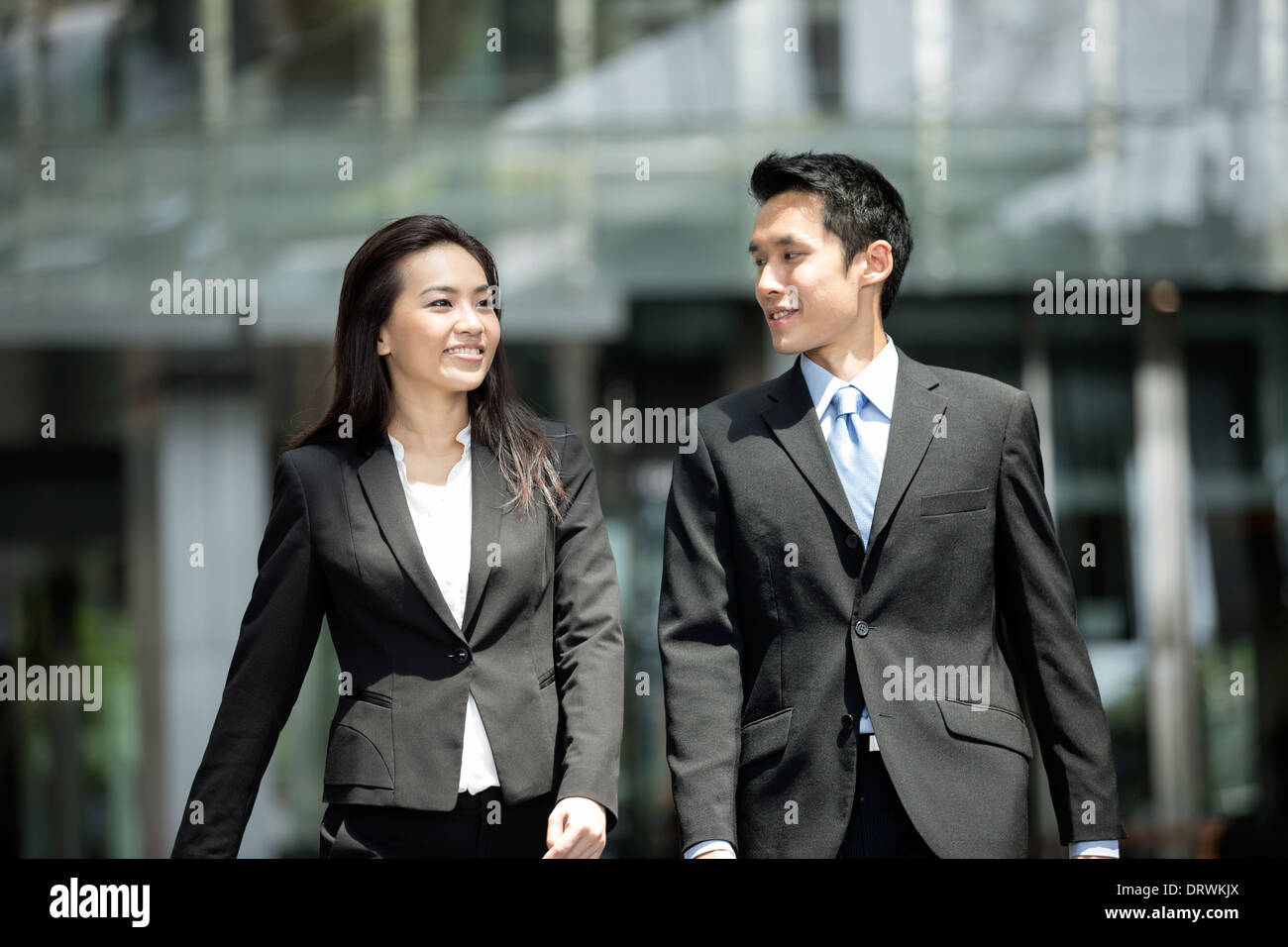 Happy Chinese Business colleagues walking outside office & talking to ...