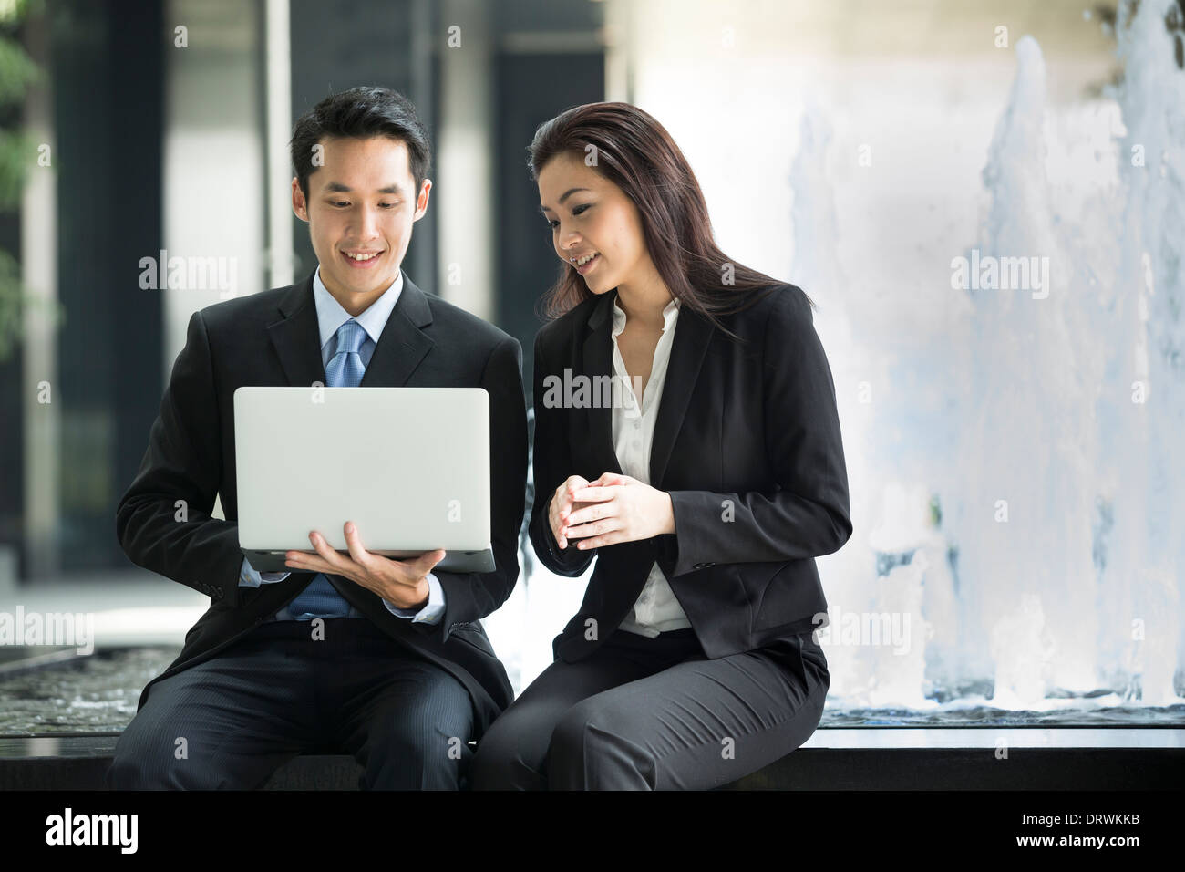 Chinese business Man and woman working together on a laptop outdoors in ...