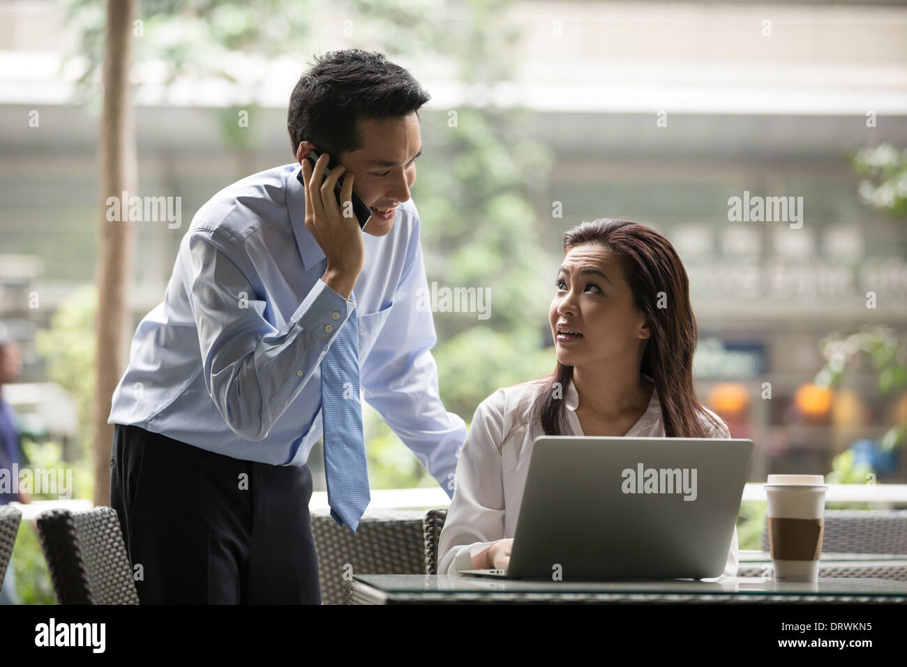 Chinese business Man and woman working together on a laptop outdoors in ...