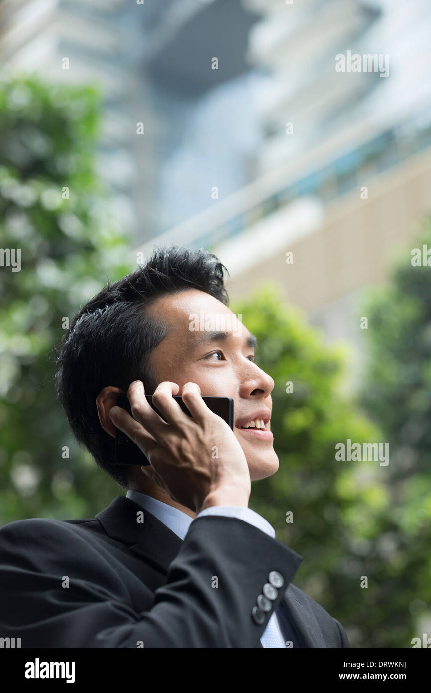 Chinese business Man using his cell phone outdoors in modern Asian city ...