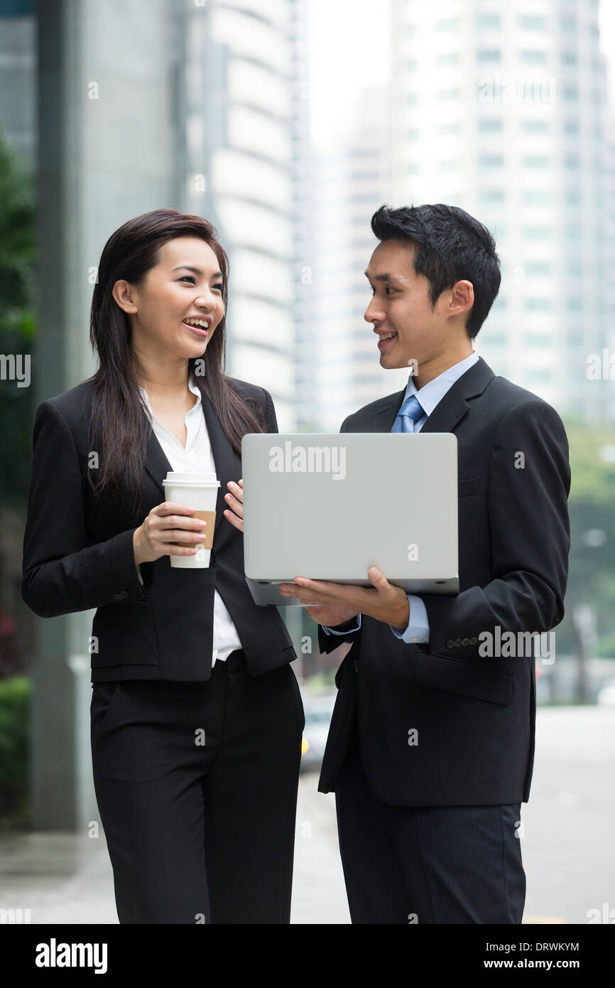 Chinese business Man and woman working together on a laptop outdoors in ...