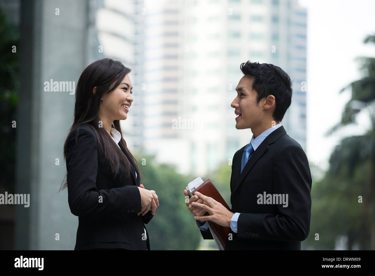 Happy Chinese Business colleagues walking outside office & talking to ...