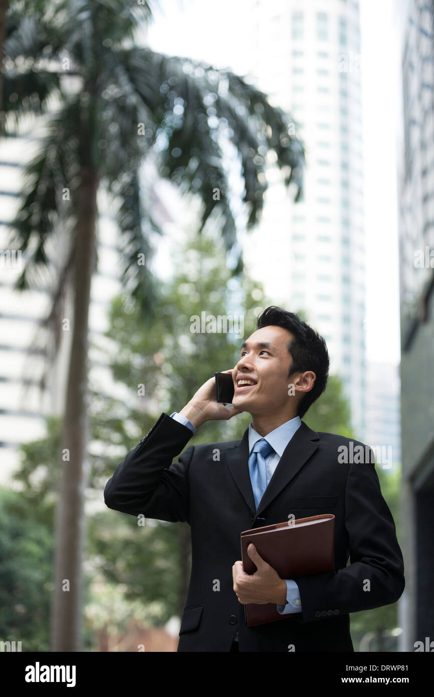 Chinese business Man using his cell phone outdoors in modern Asian city ...