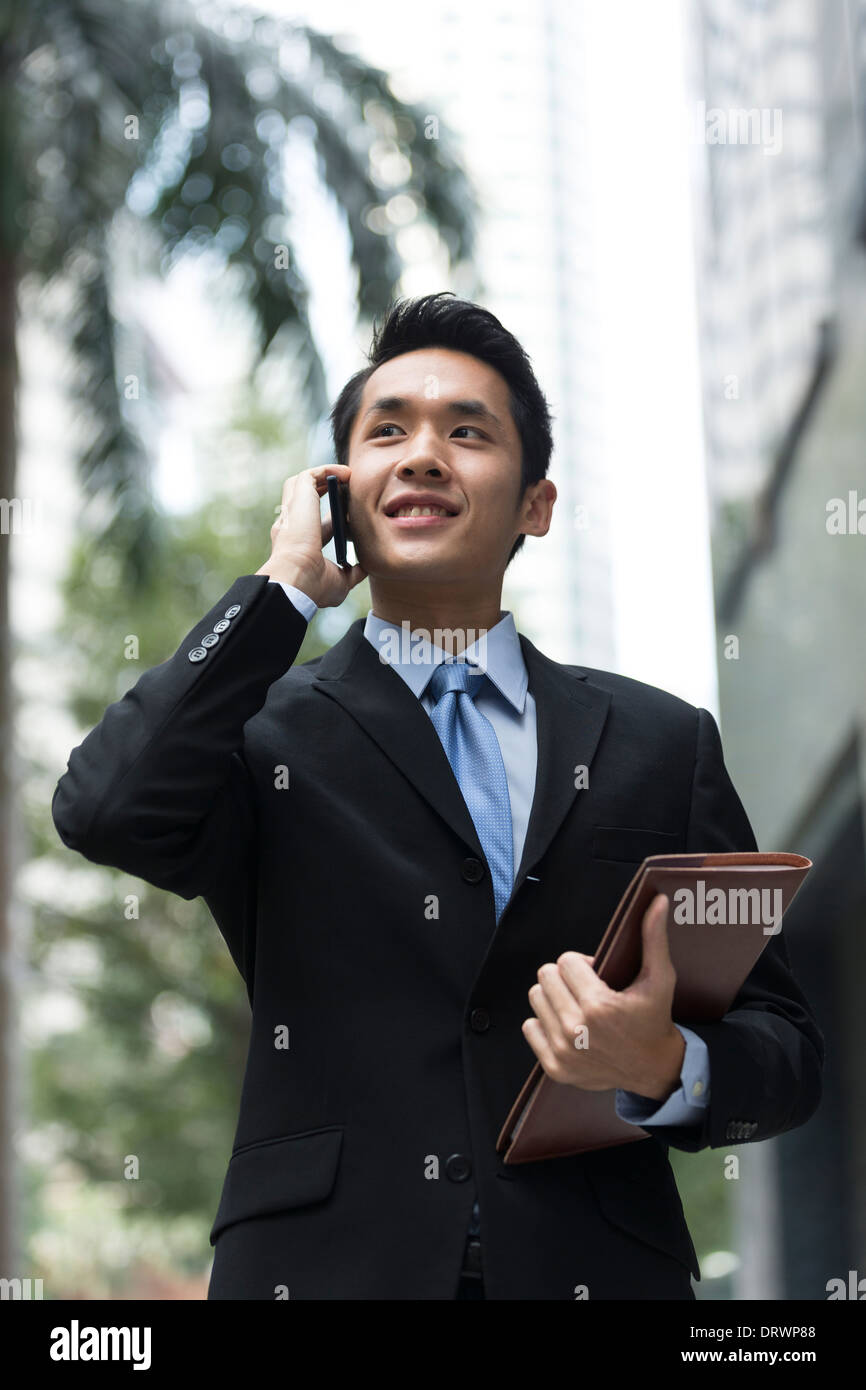 Chinese business Man using his cell phone outdoors in modern Asian city ...