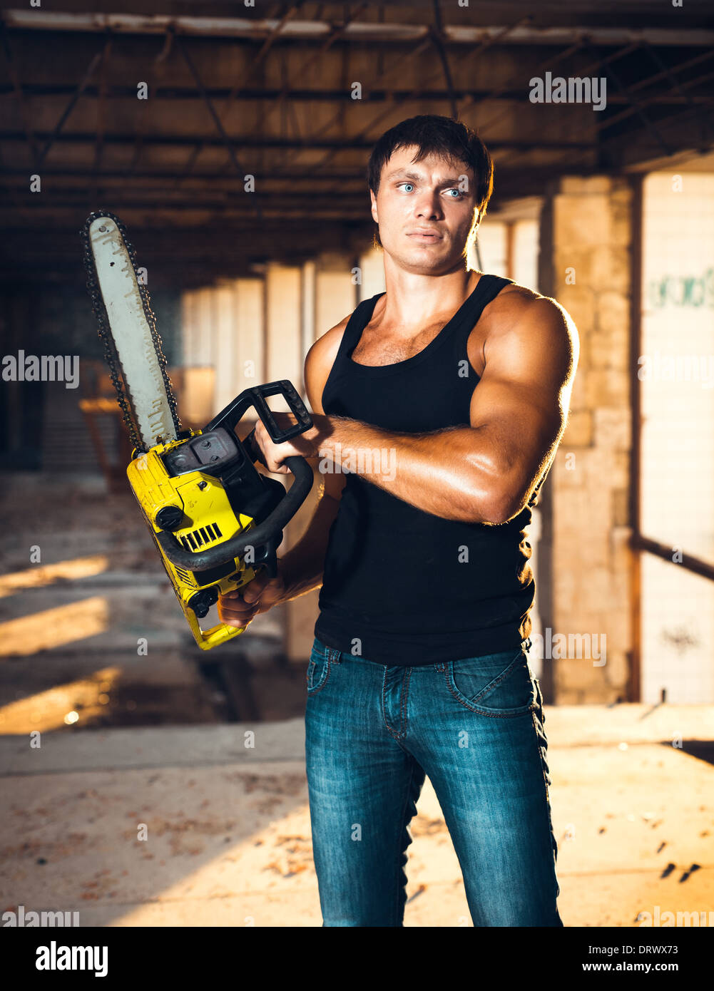 Muscular man with a chainsaw on the ruins Stock Photo - Alamy