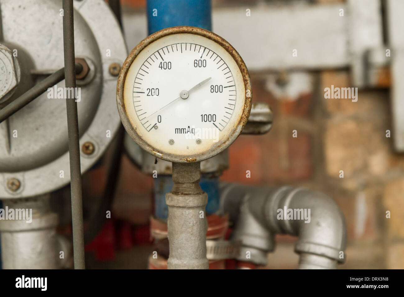 Rusty Pressure Gauge connected to pipes with brick wall behind Stock ...