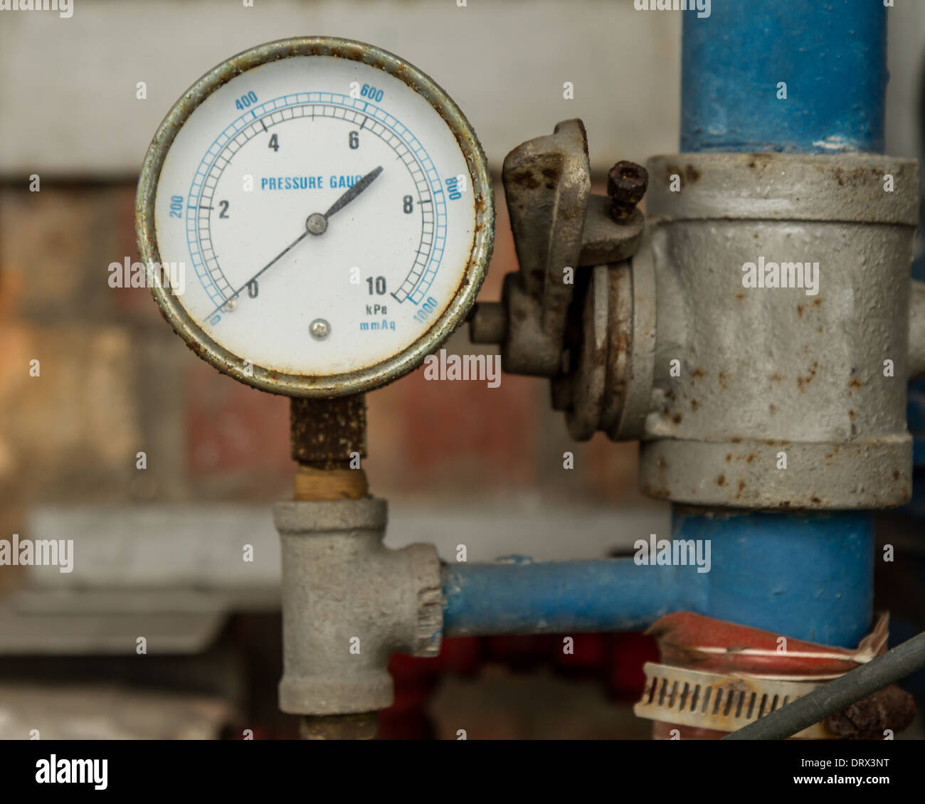 Rusty Pressure Gauge connected to pipes with brick wall behind Stock ...