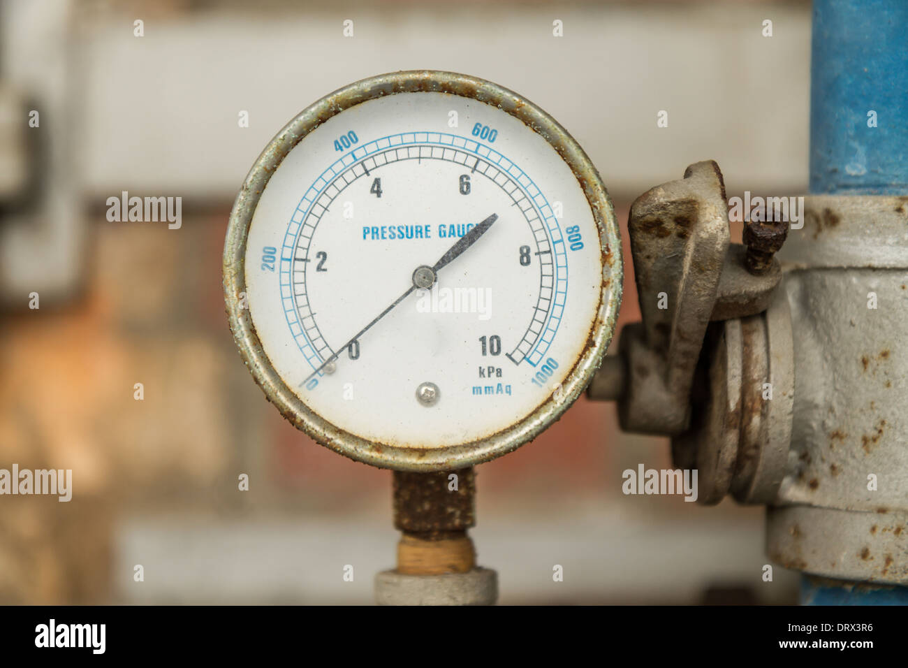 Rusty Pressure Gauge connected to pipes with brick wall behind Stock ...
