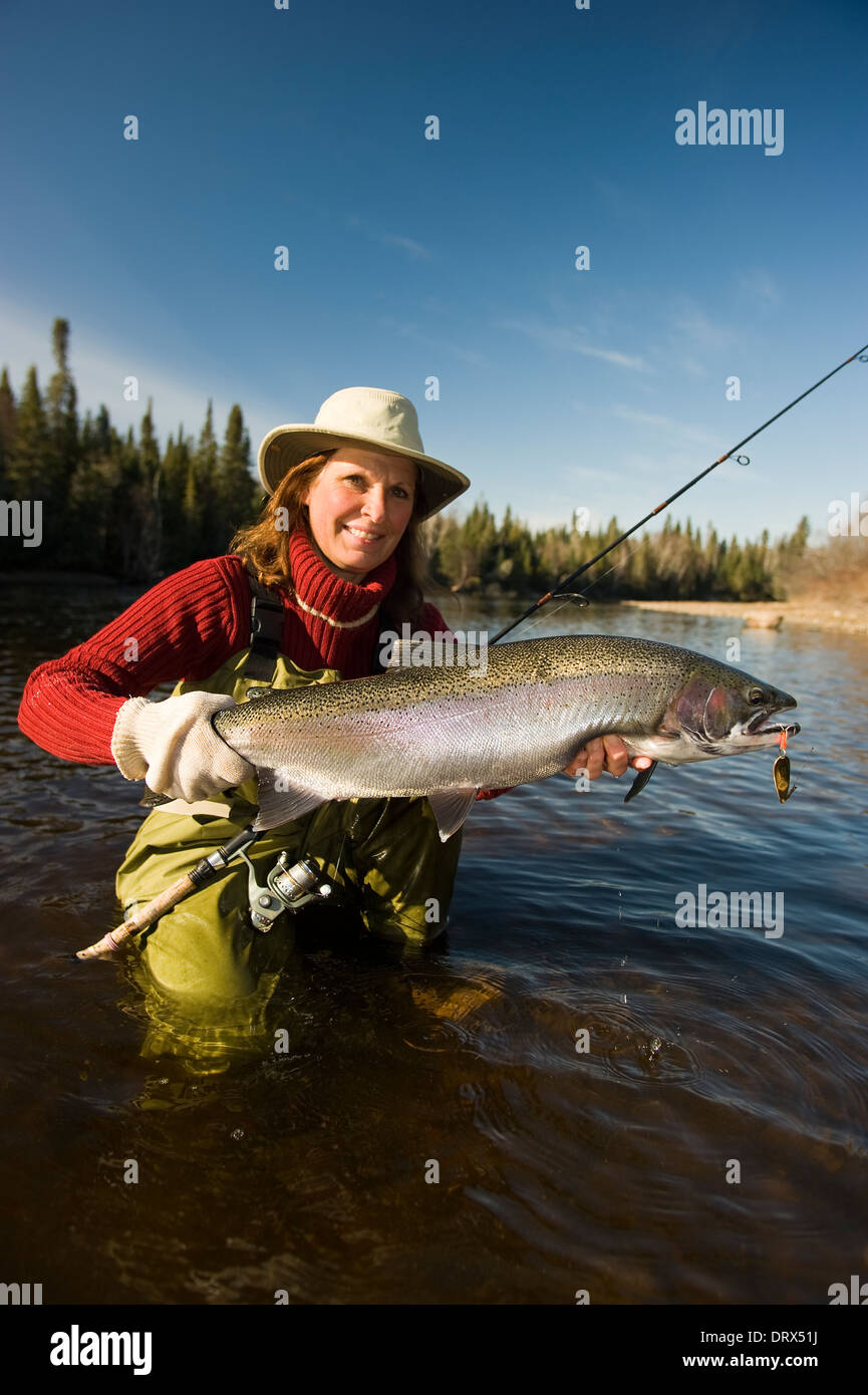 Woman angler holding a large steelhead caught in a river in Northern ...