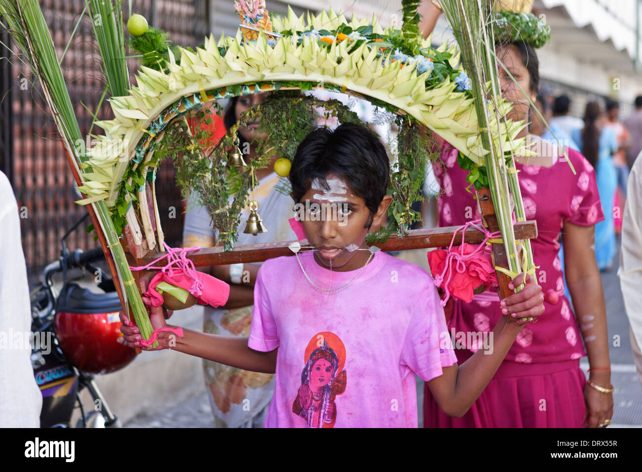 A young devotee of Lord Muruga carrying the Cavadee with his cheeks and ...