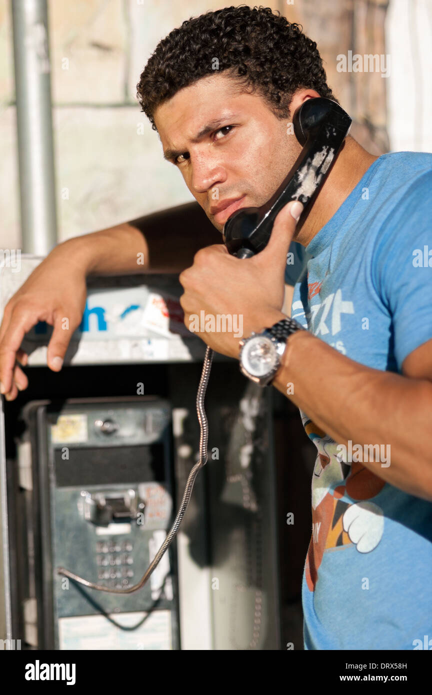 A black man making a phone call on an American public telephone. He ...