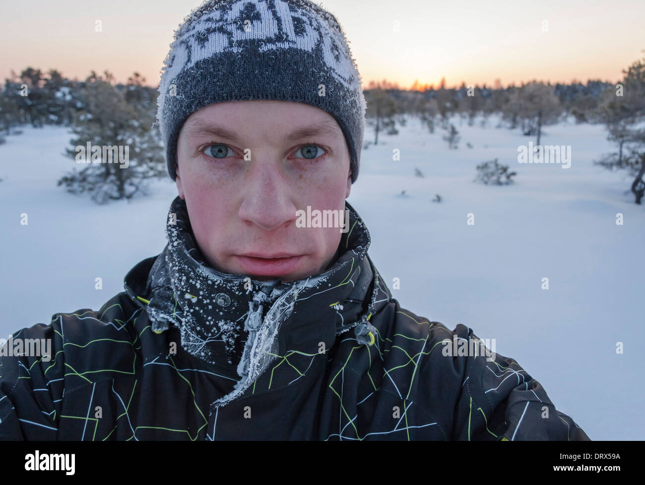 Portrait of a young man with frosty clothes and hat in a marsh early in ...