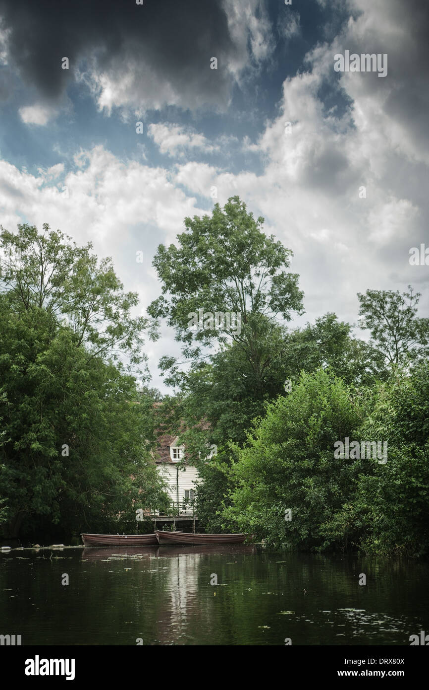 View of house next to river hidden by trees and bushes, England Stock ...