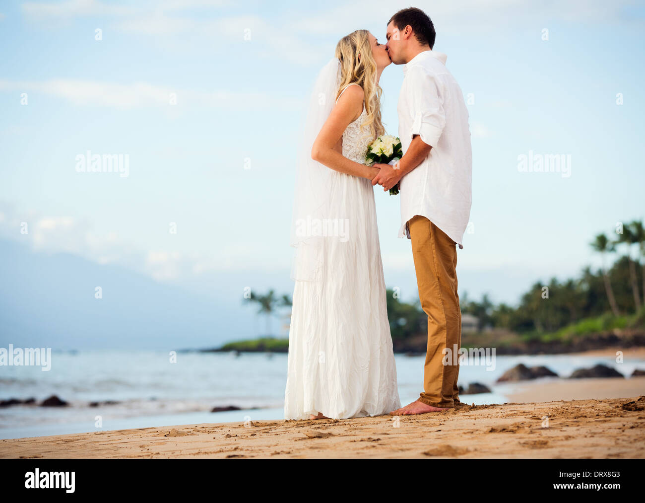 A married couple, bride and groom, at sunset on a beautiful tropical ...