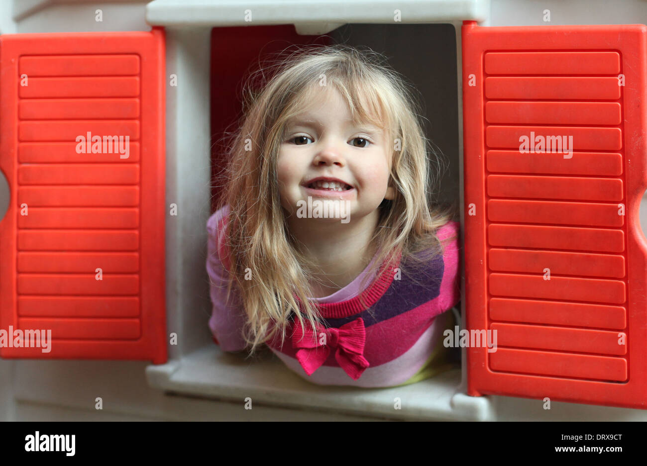 Little blond girl smiling through the window of kids playhouse Stock ...