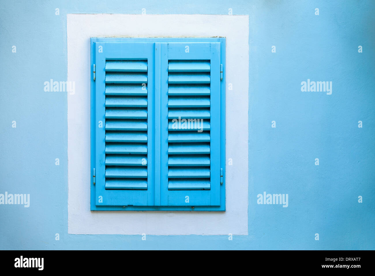 Old blue window with wooden shutters in the white frame on blue wall ...