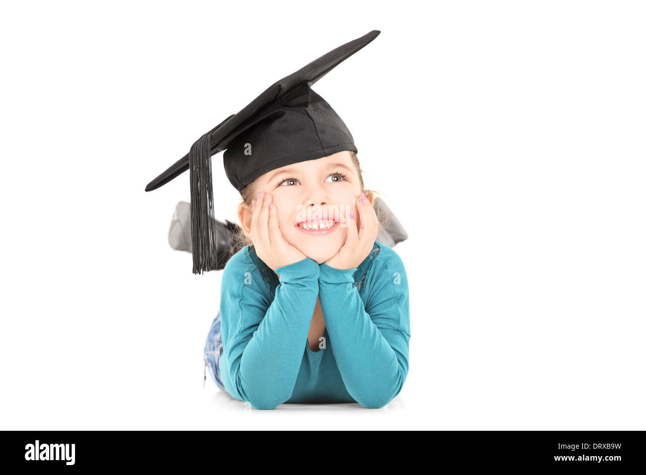Adorable little girl with graduation hat laying down and daydreaming ...