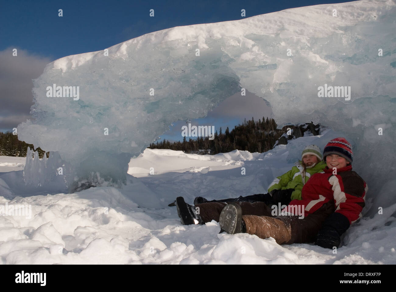 Two kids sit in the ice caves on Lake Superior in winter Stock Photo ...