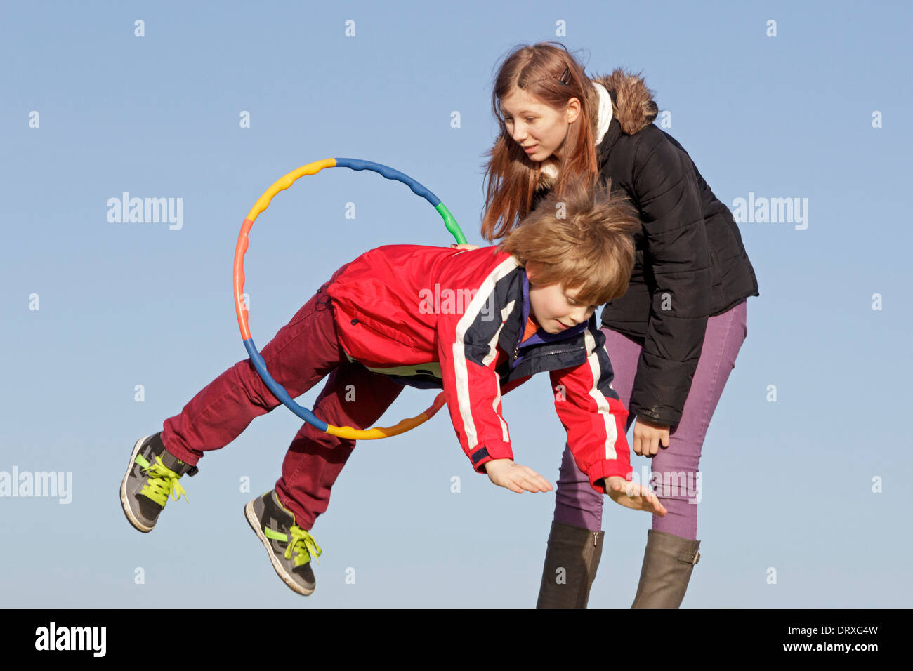 young boy jumping through a hoop held by his older sister Stock Photo ...