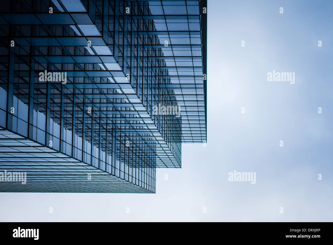 A tall skyscraper reaches to the sky. It's many windows reflecting the ...