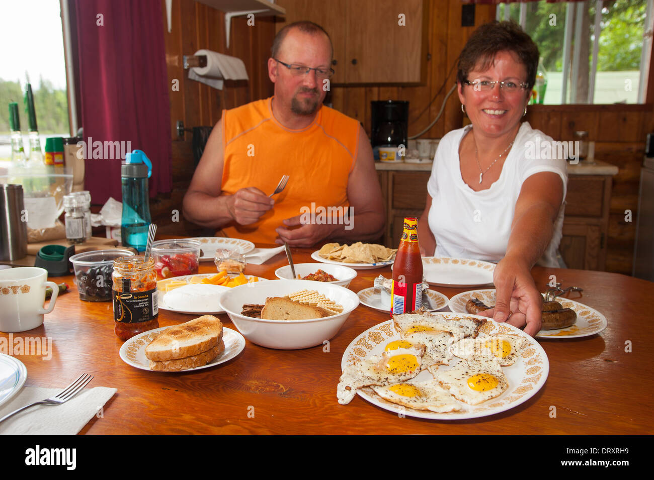 A man and woman hosting a camp breakfast in their lodge Stock Photo - Alamy
