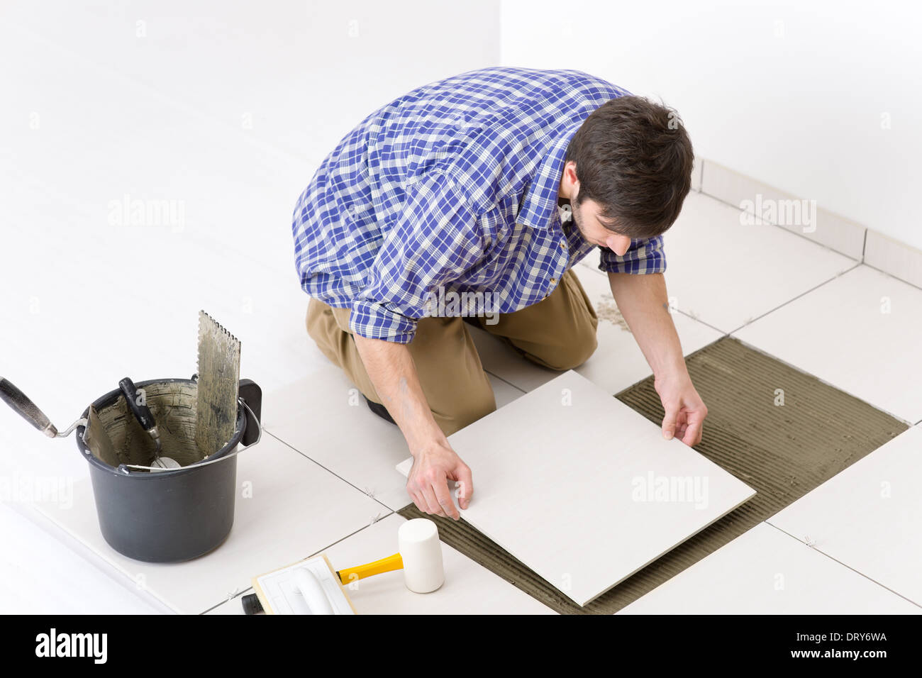 Home improvement - handyman laying tile Stock Photo - Alamy